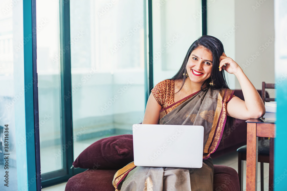 Beautiful Indian young woman in a saree using her laptop, working from ...