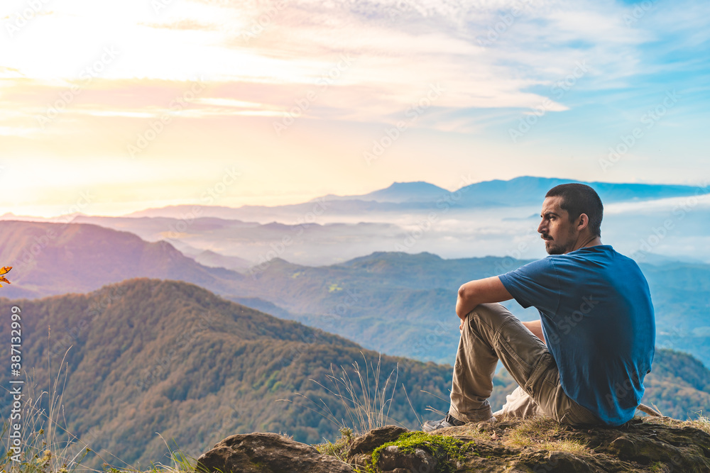 Man sitting on a edge of a cliff and looking at beautiful and rough ...
