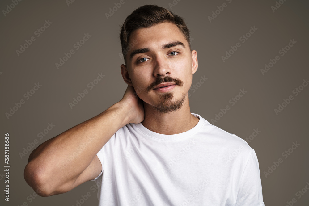 Image of caucasian handsome guy rubbing his neck while posing on camera ...