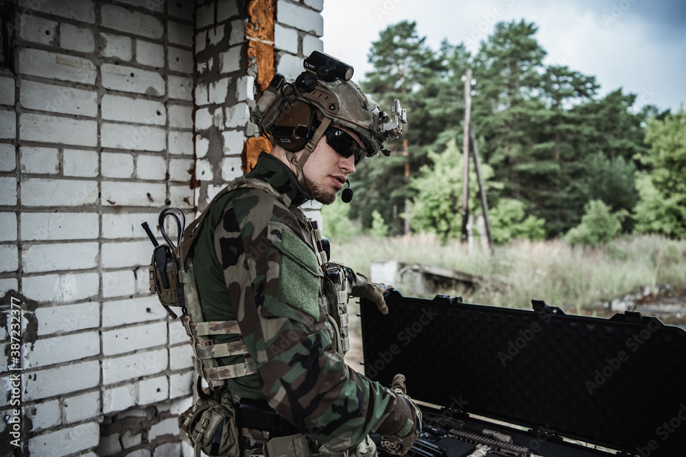 Military man with gun case takes out an assault rifle in destroyed city ...