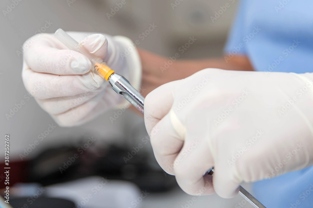 Hands of female dentist doctor wear white gloves putting needle into ...