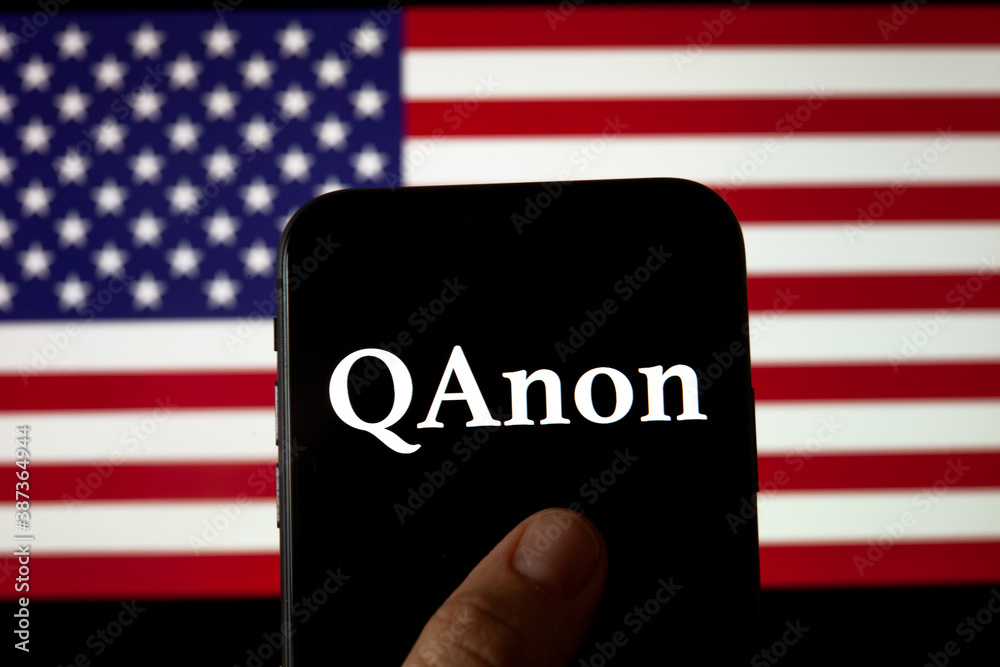 QAnon organisation logo seen on the smartphone which is placed on USA ...