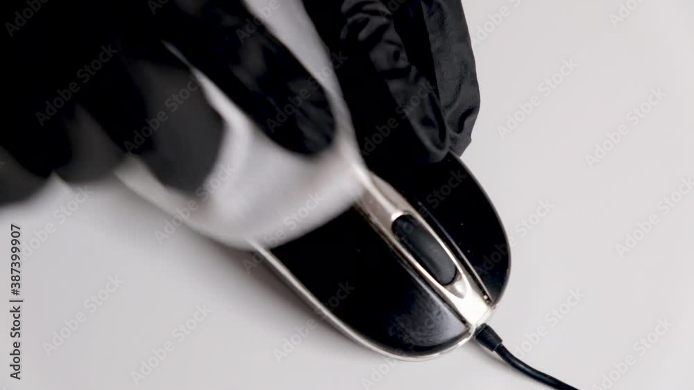Hands in black gloves cleaning a wired computer mouse with wet wipe ...