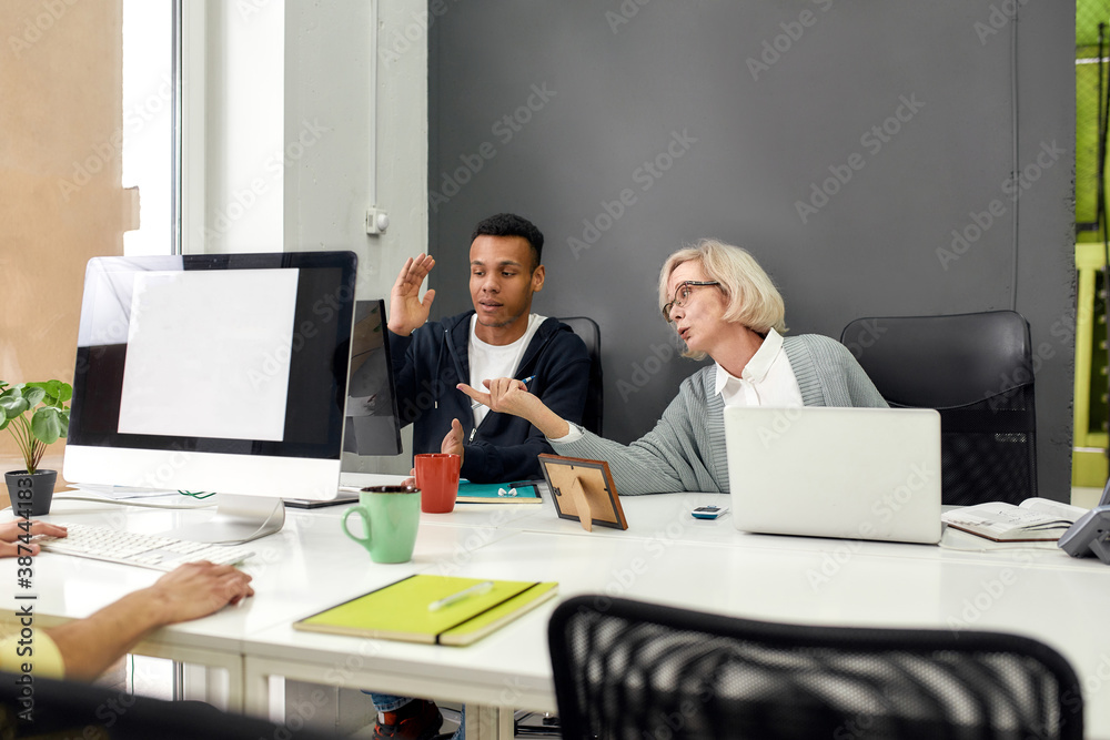 Friendly aged woman, female worker training or teaching new employee ...