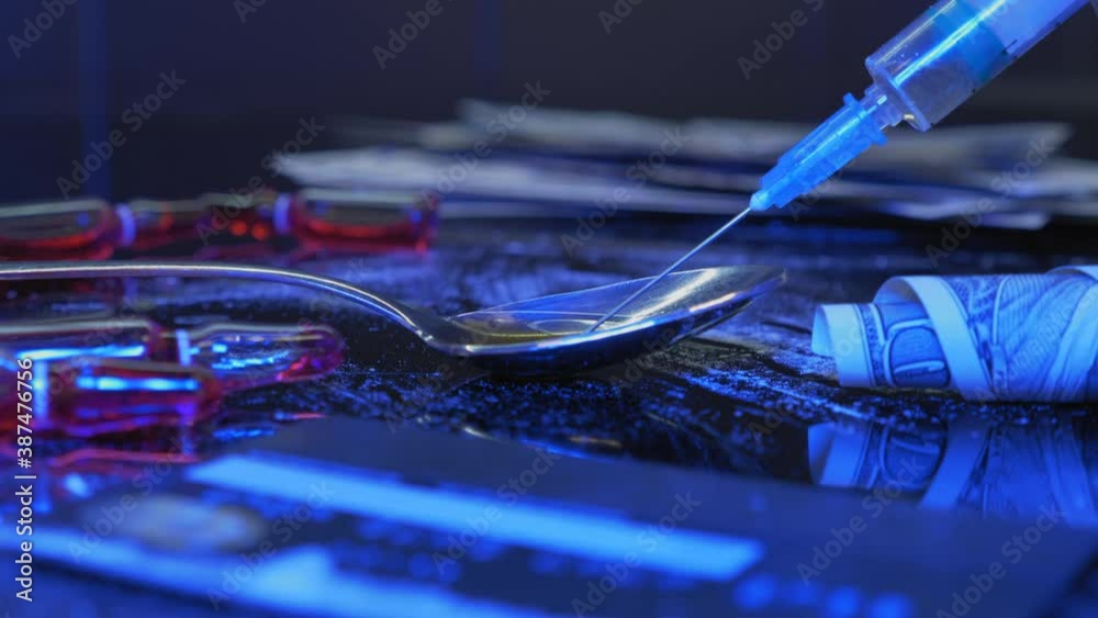 Addict is filling syringe with heroin from spoon, close up. Man is ...