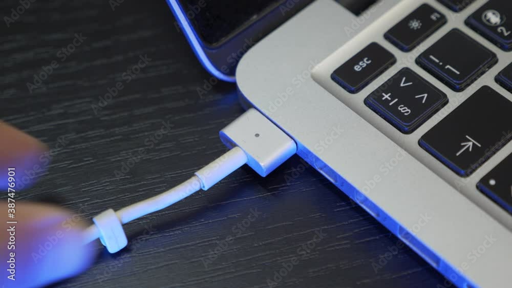 Male hand is connecting laptop charger. Laptop computer with USB type C ...