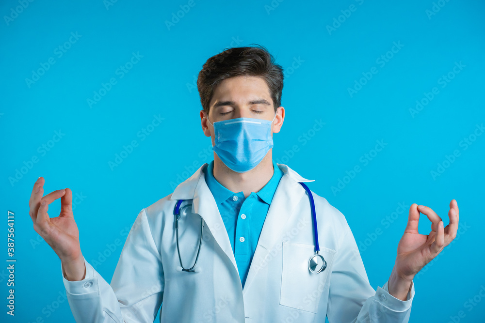 Calm doctor in mask relaxing, meditating. Man calms down, breathes ...