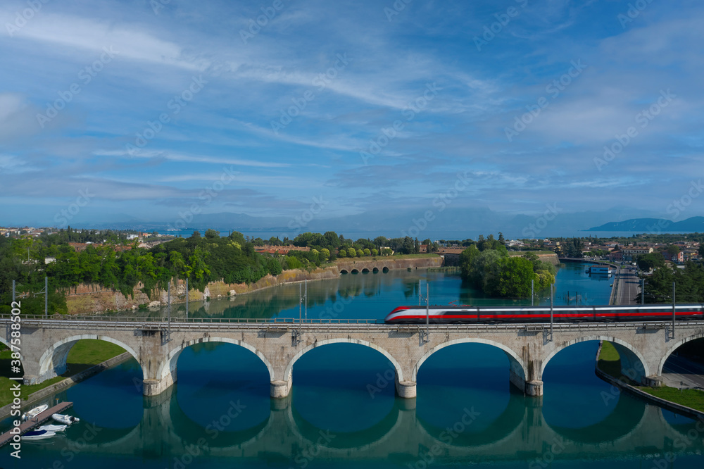 Blurred train movement on arch bridge over the river against the ...