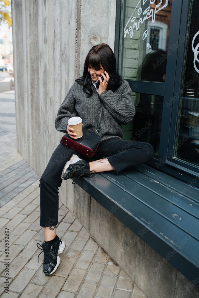Eccentric young woman sitting on the sill bench with one leg up ...