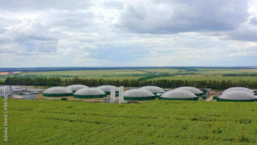 Biogas production in summer. Storage tanks of biogas plant on green fields. Renewable energy ...