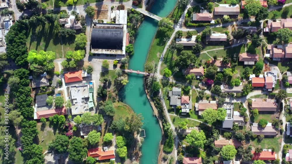 Aerial pass over Kibbutz Nir David with Asi river channel turquoise ...
