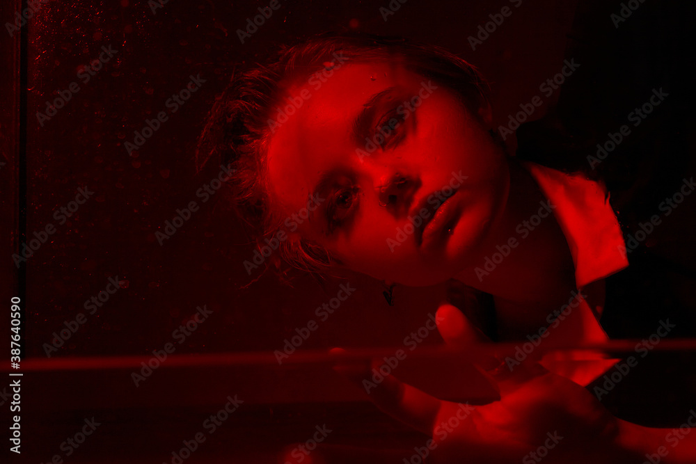 Horrible portrait of a young girl in a horror room with a red light ...