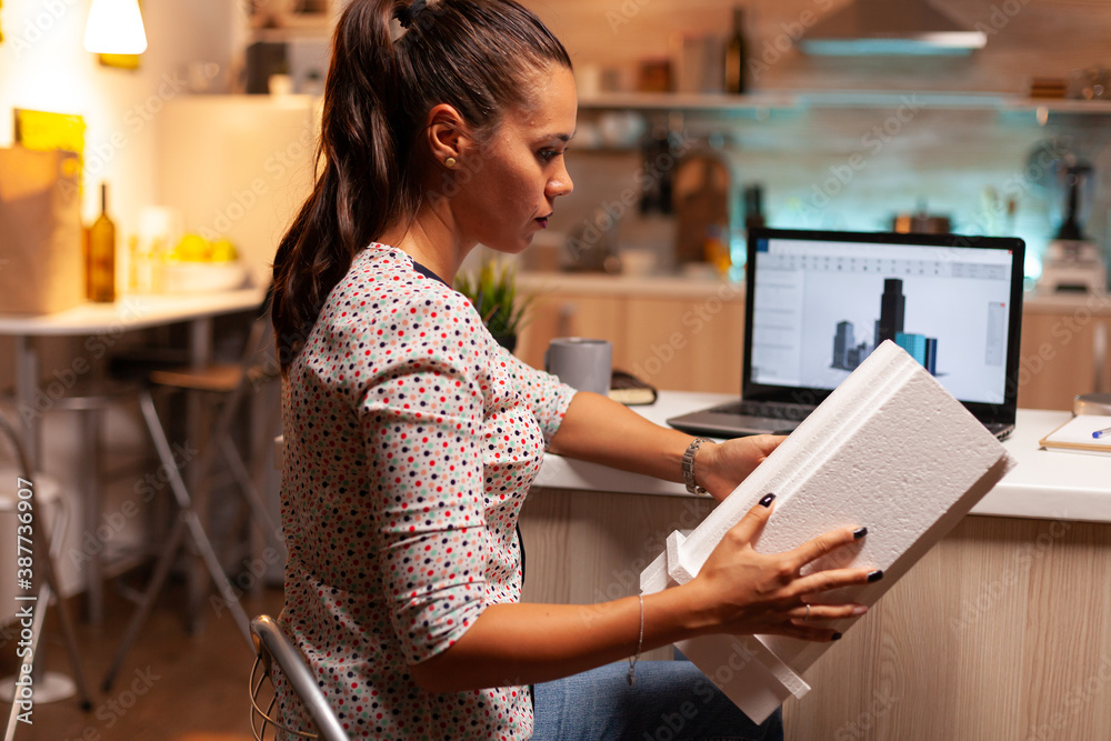 Female architect looking at building model during late night time in ...