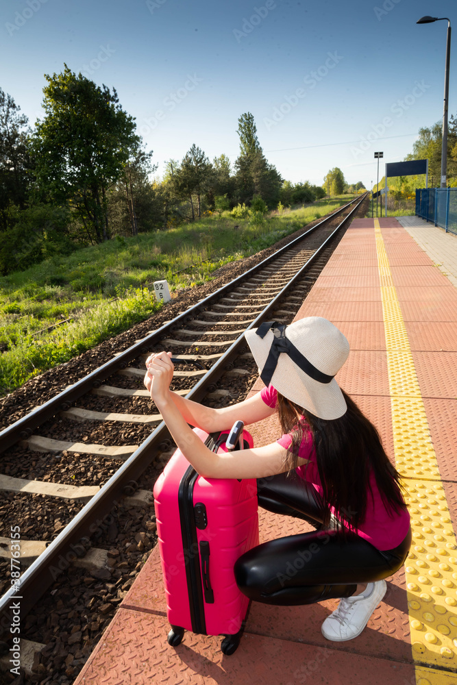 An adult teenager waiting on a train platform for a late train for a ...