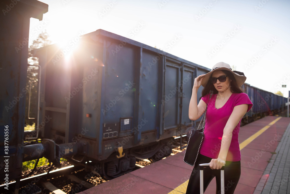 The girl holds her big hat so that the blast from the freight train ...
