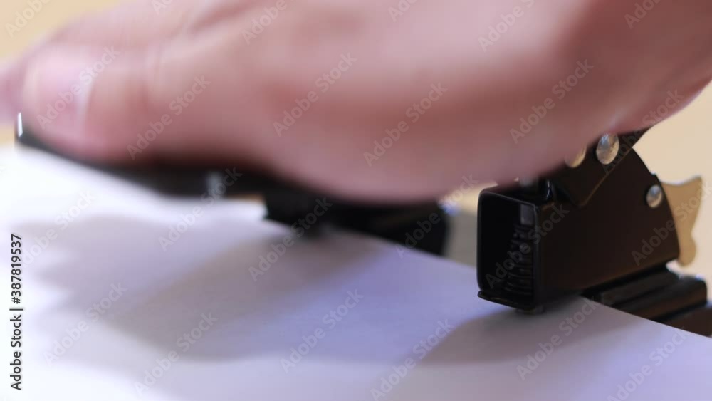Man's hand makes holes in sheet of paper with a hole punch. Stock Video ...