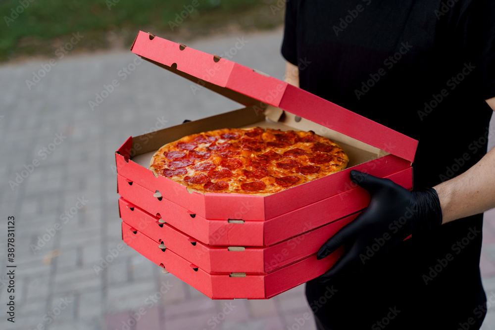 Safety pizza delivery from restaurant. Food courier in black medical ...