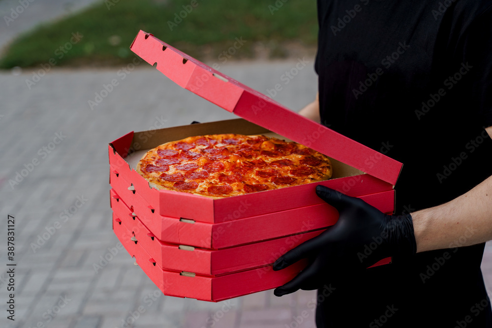 Foto de Safety pizza delivery from restaurant. Food courier in black ...