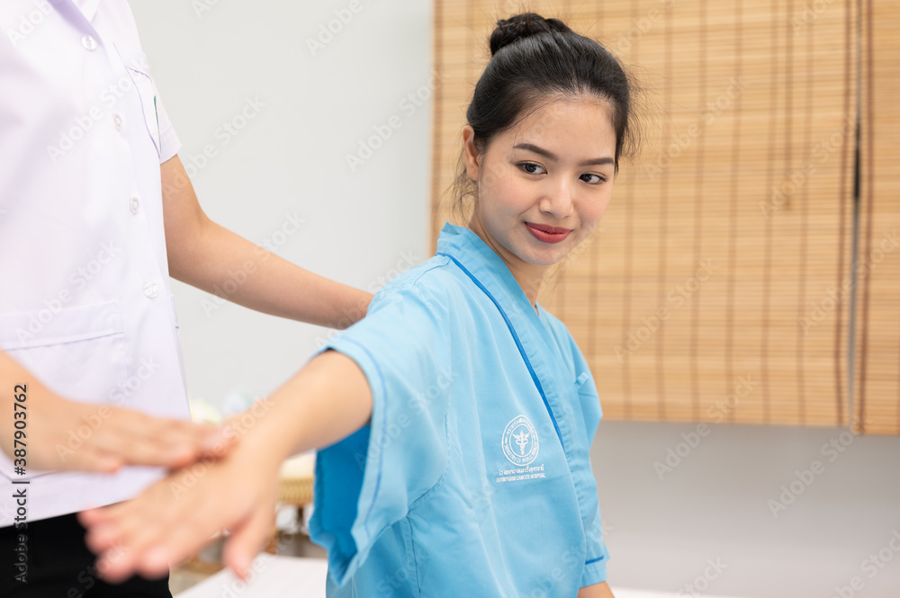 Physiotherapist giving physical therapy to Asian young woman patient in ...