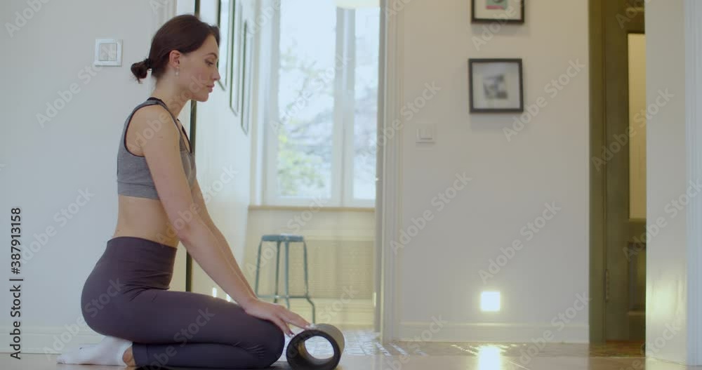 Slim woman unrolling mat before yoga practice indoors natural light ...