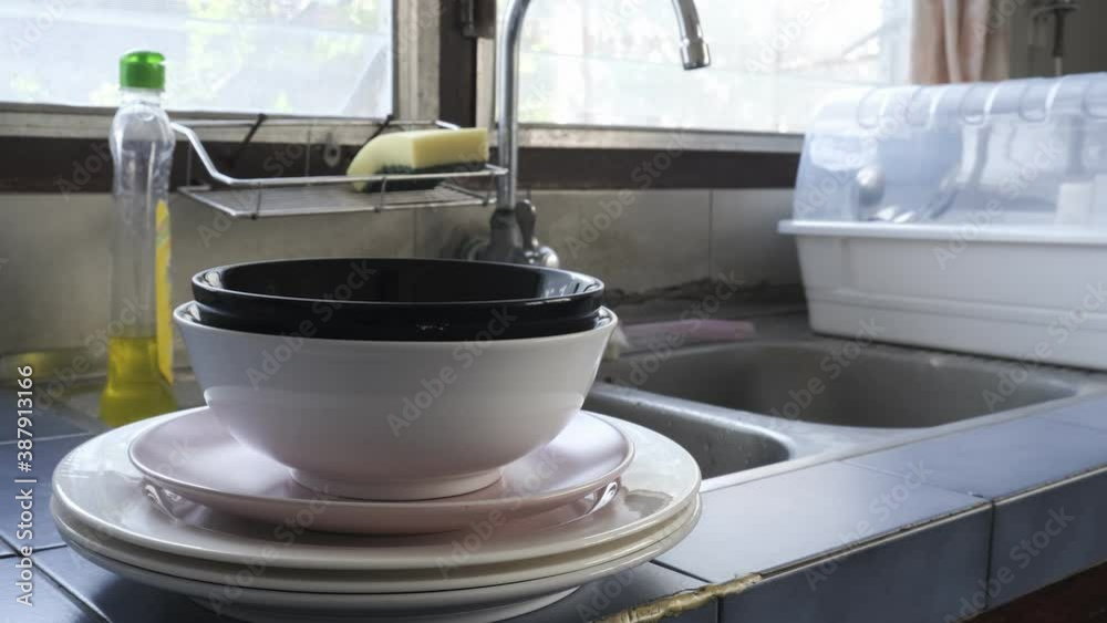 plates and cups are stacked on top of the sink in the domestic kitchen ...