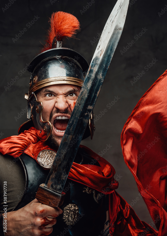 Mad roman soldier with blood on his face and dark armour screaming and ...