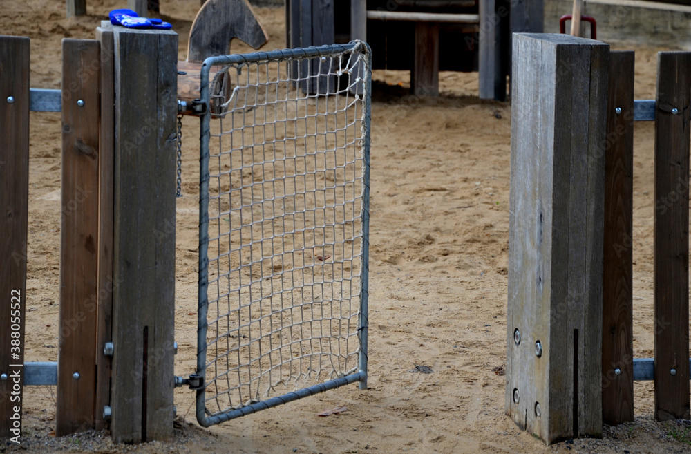 at a children's playground separated by a metal gate with a net string ...