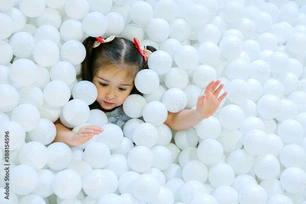 Little girl in a big pool filled with white plastic balls Stock Photo ...