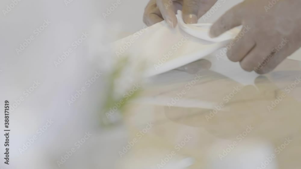 A waiter is starting to fold a white napkin into a fancy figure to ...