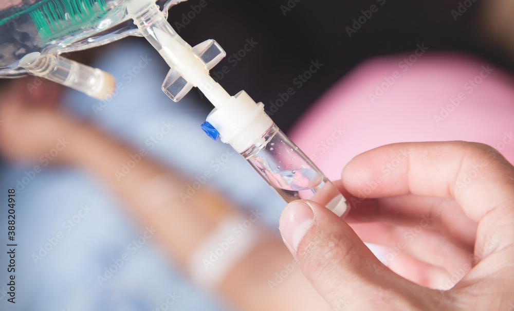 Male hand connecting an intravenous drip in home. Stock Photo | Adobe Stock