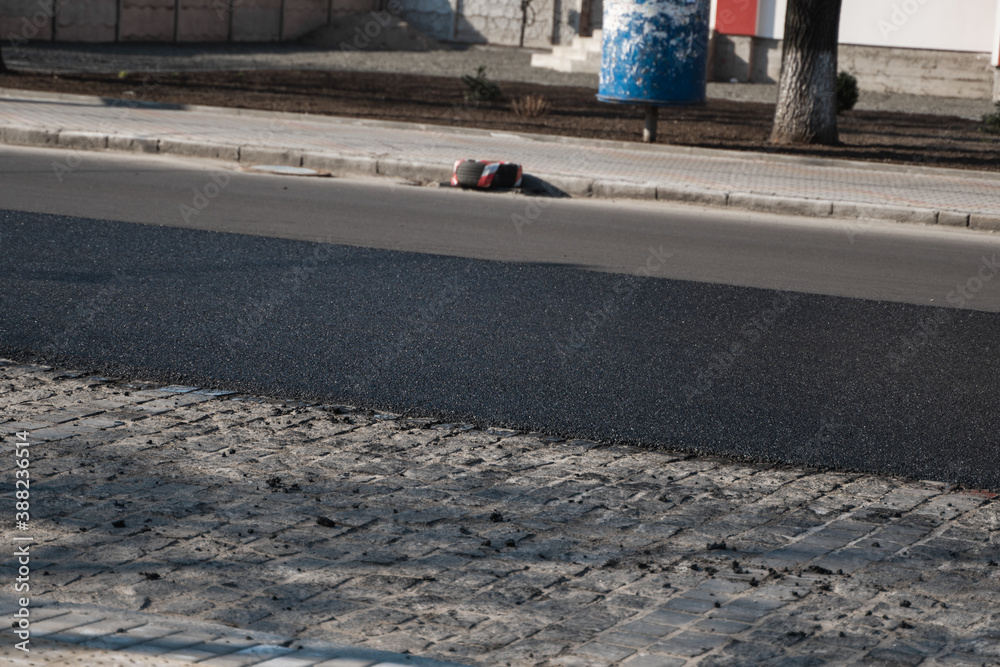 Freshly laid black bitumen asphalt with a high edge to the gravel ...