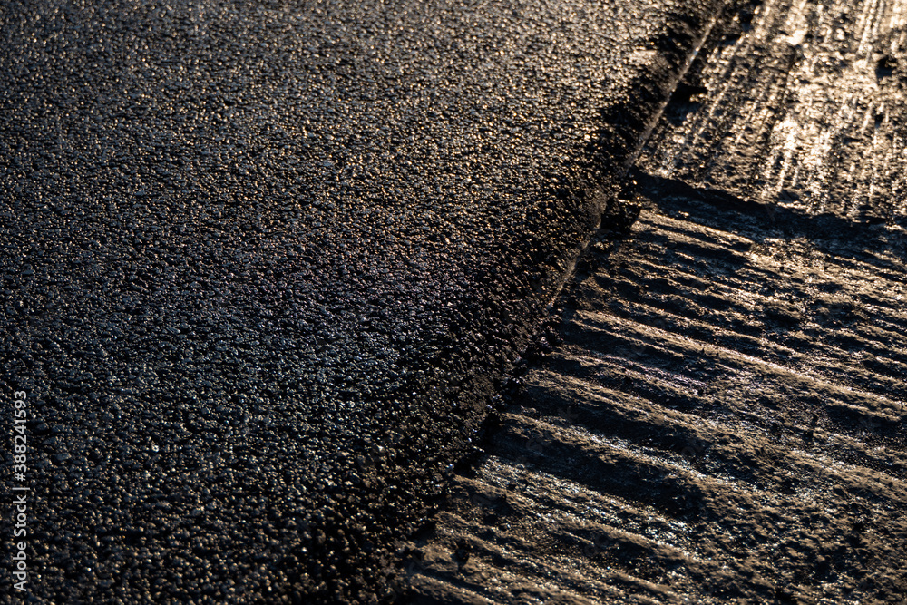 Freshly laid black bitumen asphalt with a high edge to the gravel ...