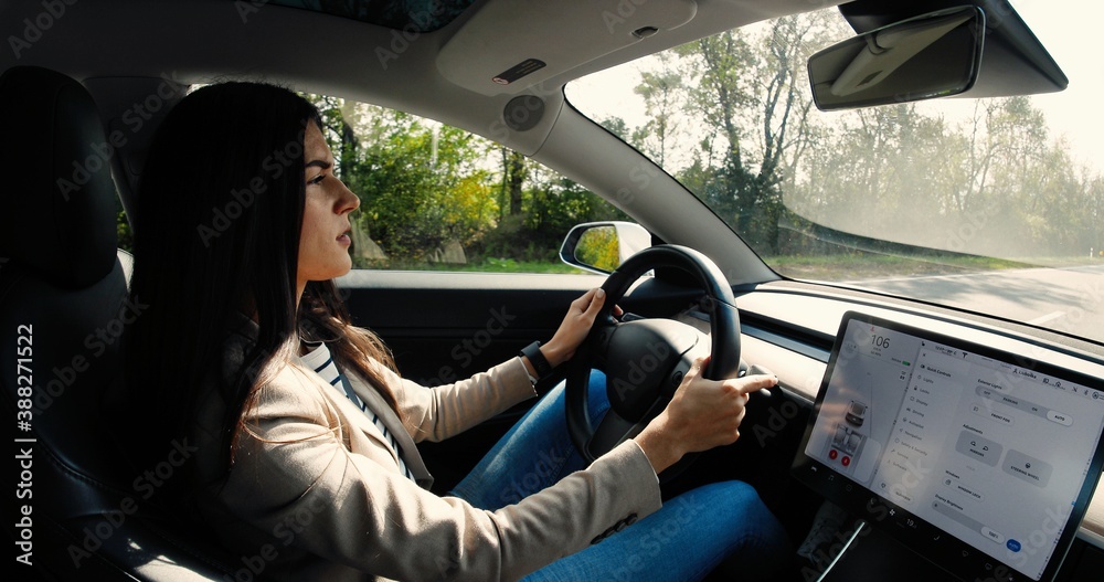 Side view of young happy Caucasian woman traveling in self-driving ...