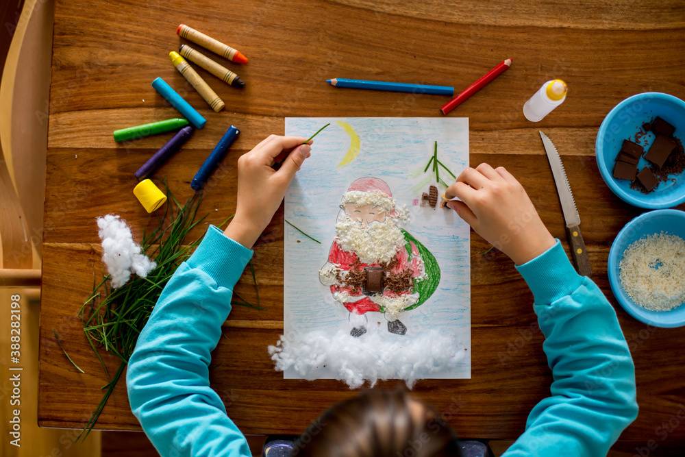 School child, boy, drawing a picture of Santa Claus and decorating him ...