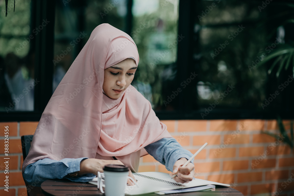 Muslim female student taking down note in diary. Concentrated girl ...