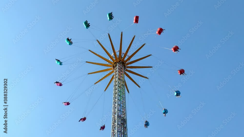 Vertical colorful chain fair swing spinning people around, symmetrical ...