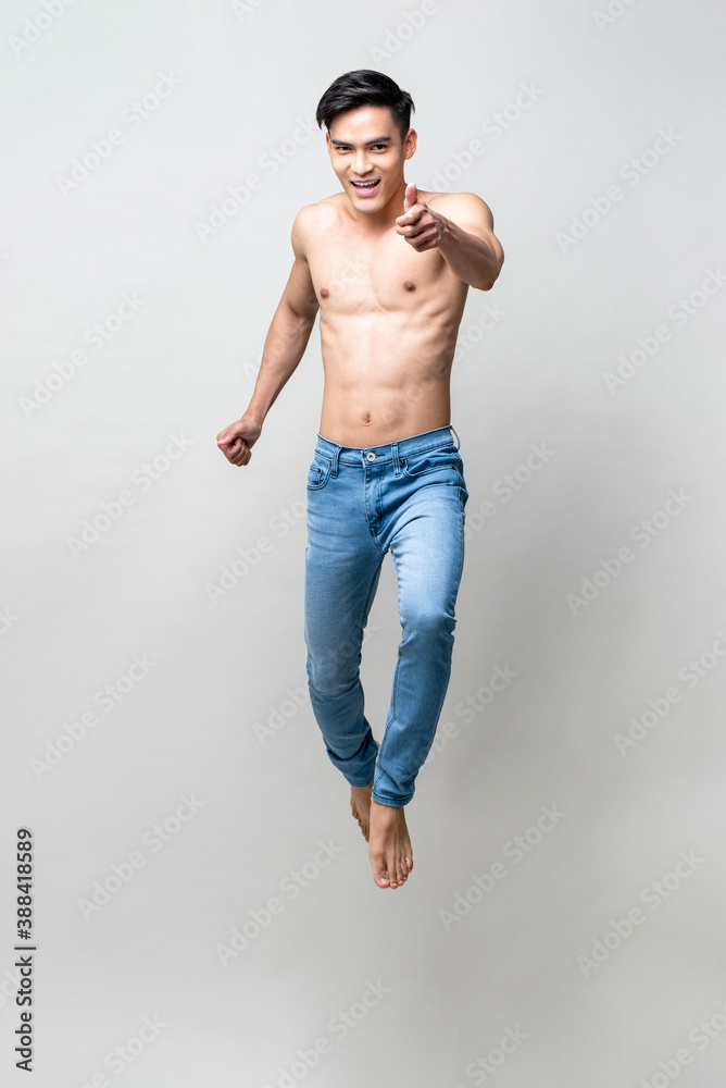 Full length portrait of energetic handsome shirtless Asian man jumping ...