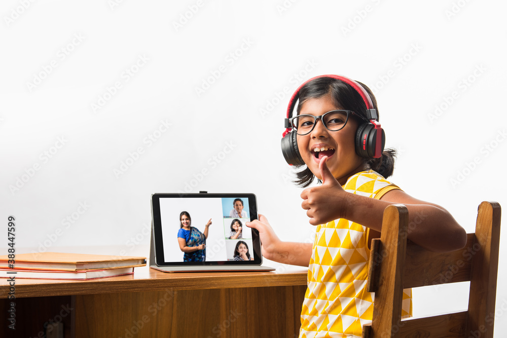 Indian girl studying using laptop or tablet during home schooling ...