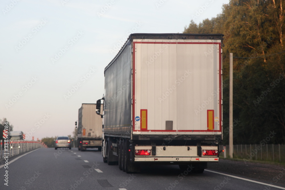 European heavy trucks with white semi trailers van drive on two lane ...