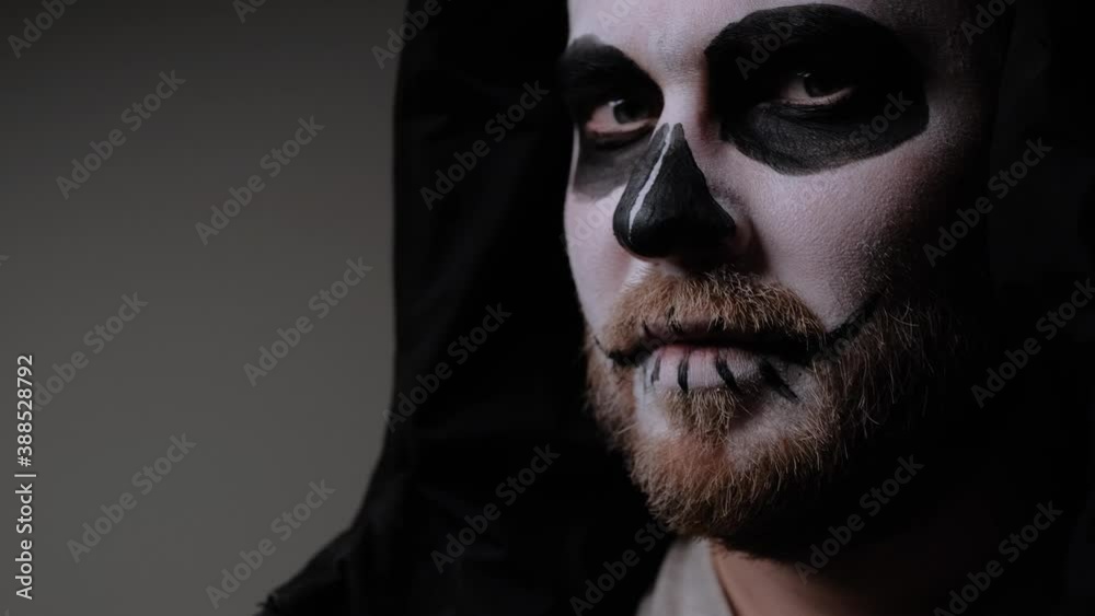 Man, disguised as a zombie, with a beard and a black hood on his head ...