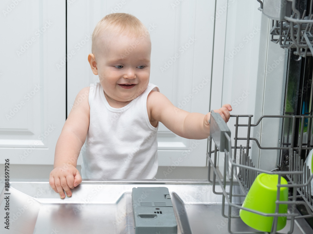 baby blonde boy in white clothes helping in the kitchen using ...