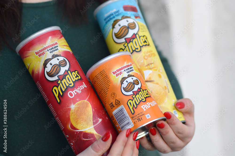 Young girl holds few pringles potato chips cylinder packs. Pringles is ...