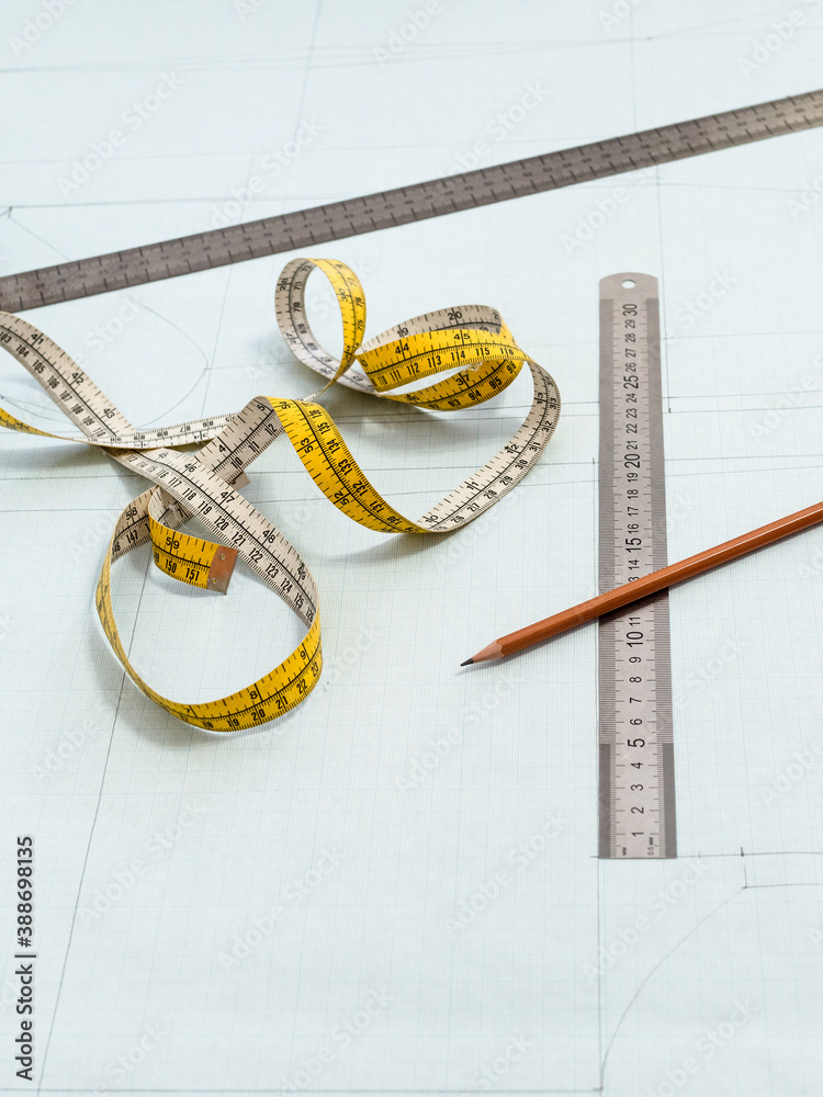 measuring tape, rulers and pencil on pattern layout of dress drawn on ...