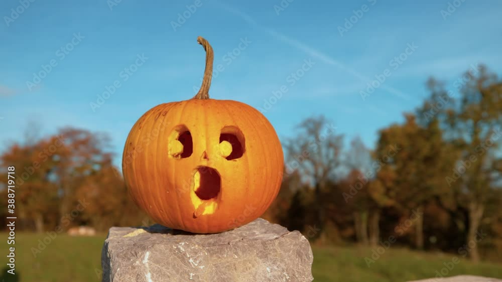 REVERSED SUPER SLOW MOTION, CLOSE UP: Big carved pumpkin with a shocked ...