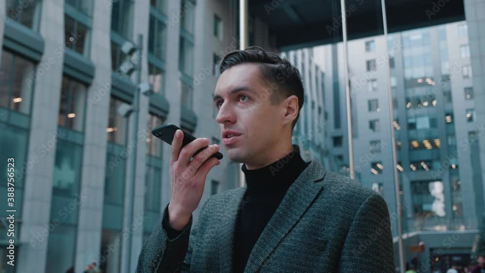 Businessman use smartphone to send voice messages outdoors at downtown ...