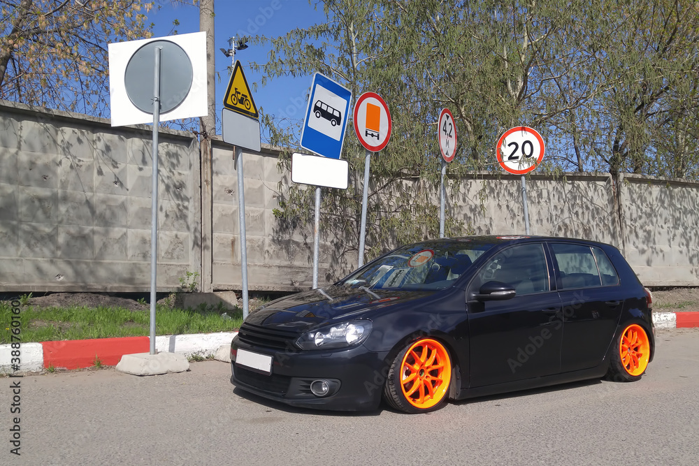 Black hatchback with orange wide wheels tuned by air suspencion parked ...