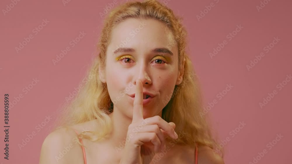 Portrait of emotional blonde female saying shh, asking for silence or ...