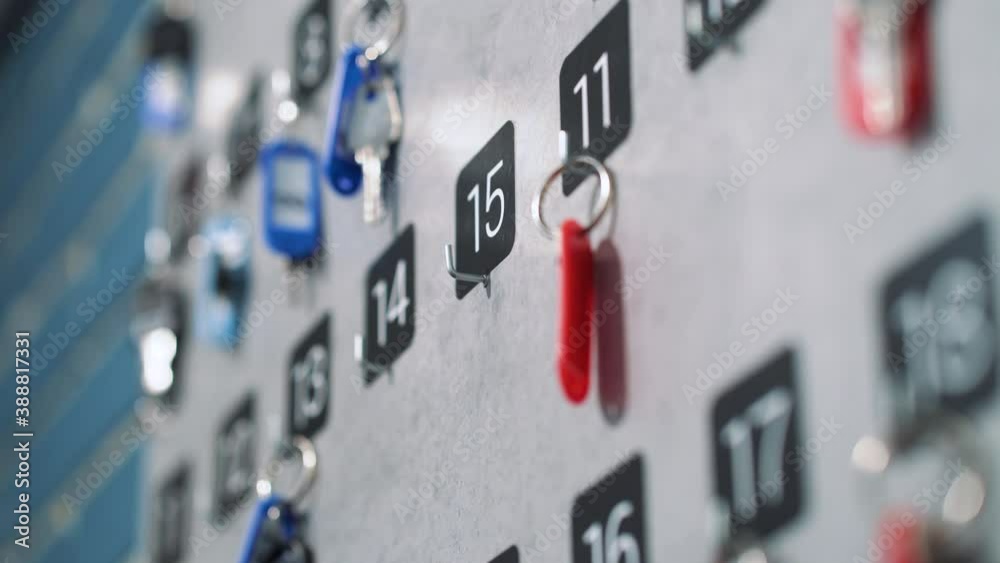 Female hand taking key with fifteen badge from reception board. Closeup ...