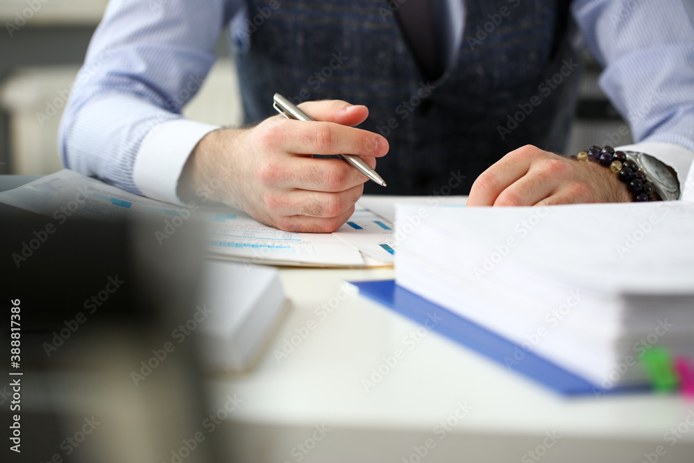 Clerk man at office workplace with silver pen in arms do paperwork ...