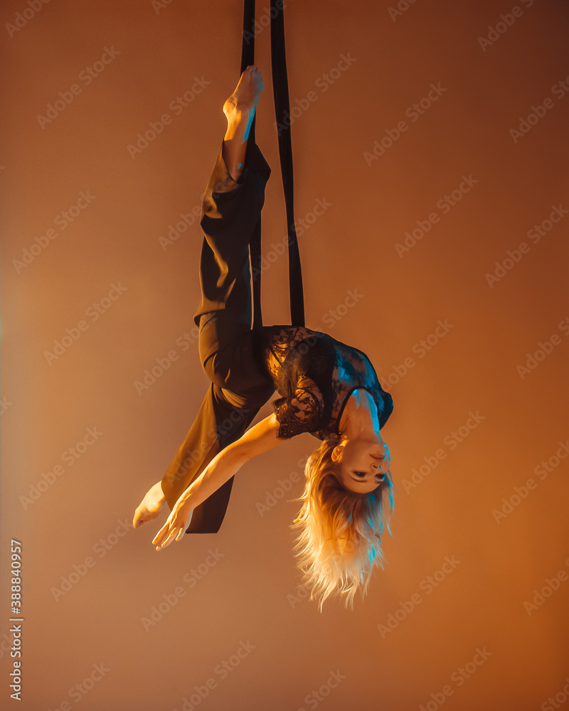 young girl in black costume is making aerial trick upside down on the ...
